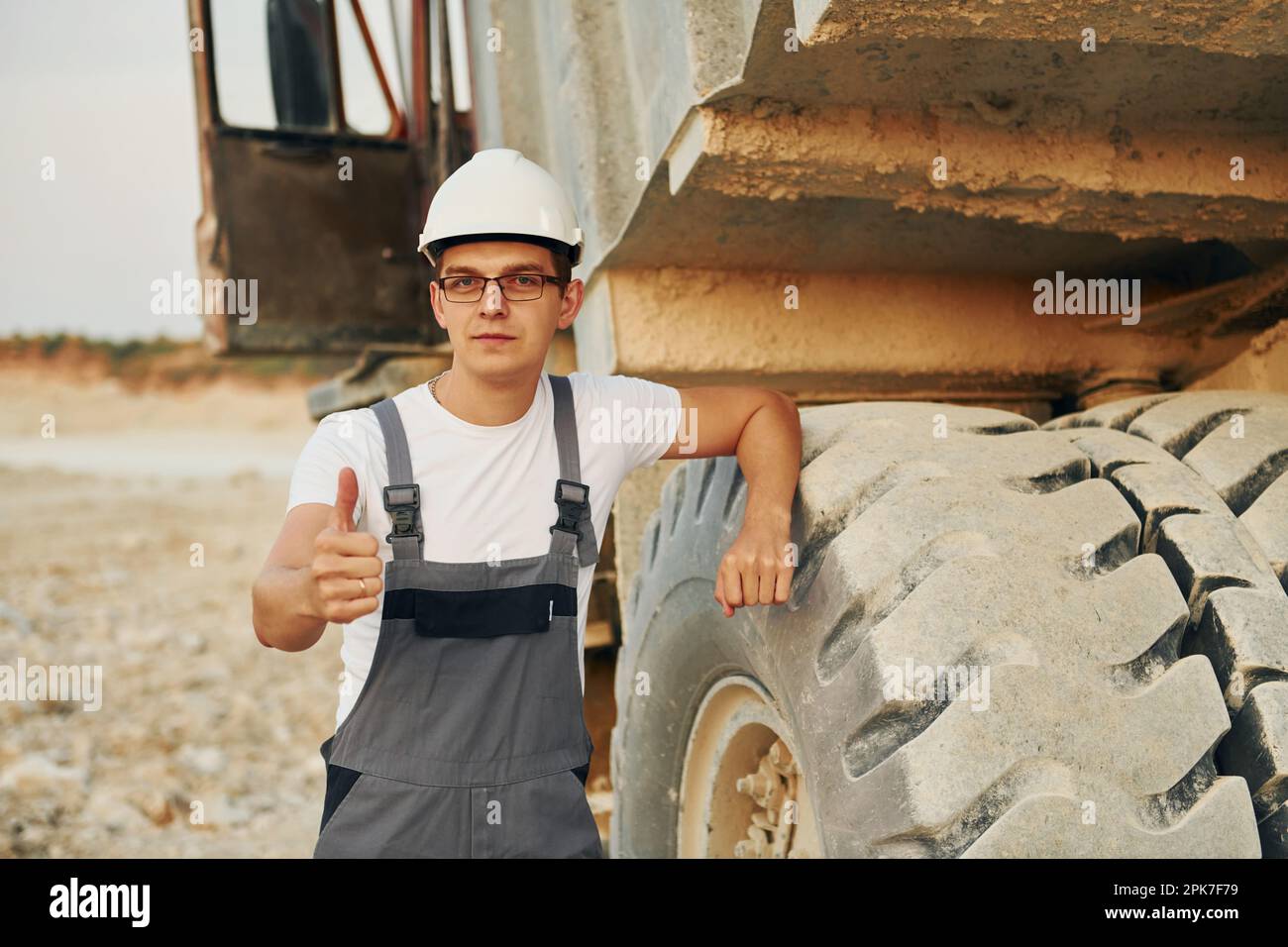 Near loading vehicle. Worker in professional uniform is on the borrow pit at daytime Stock Photo ...