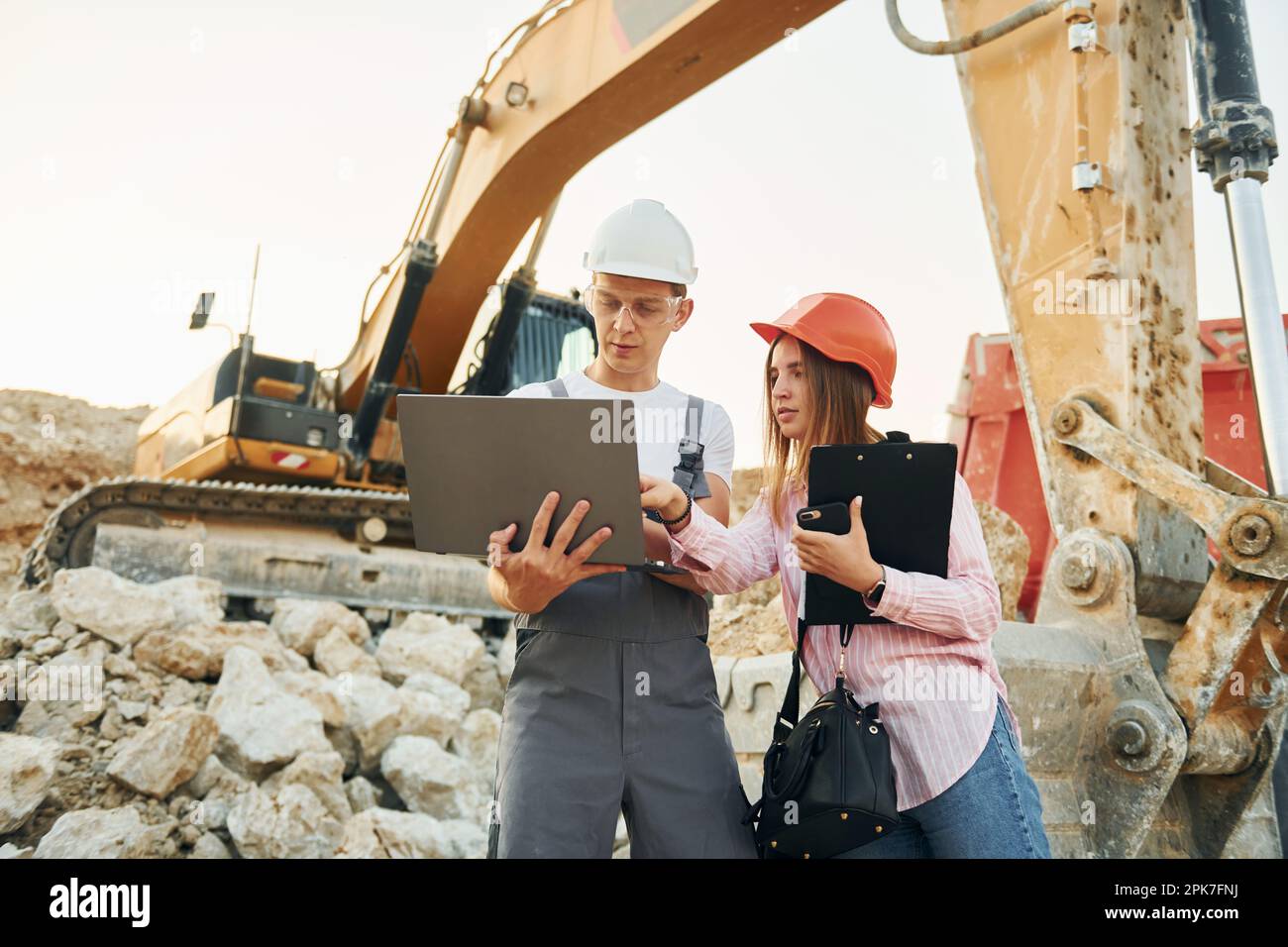 Using laptop. Two workers is on the borrow pit at daytime together Stock Photo - Alamy