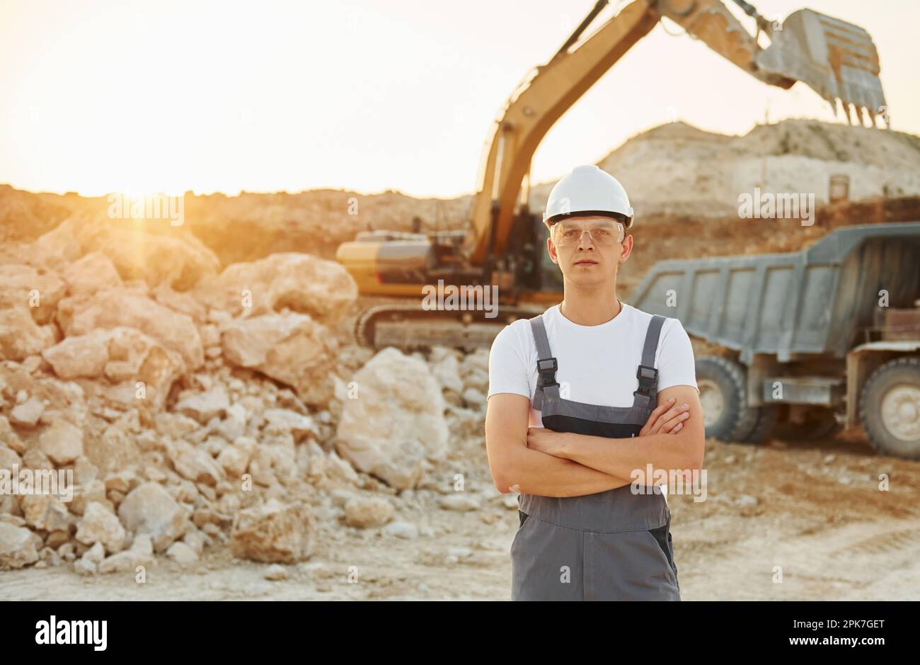 Standing with arms crossed. Worker in professional uniform is on the borrow pit at daytime Stock ...