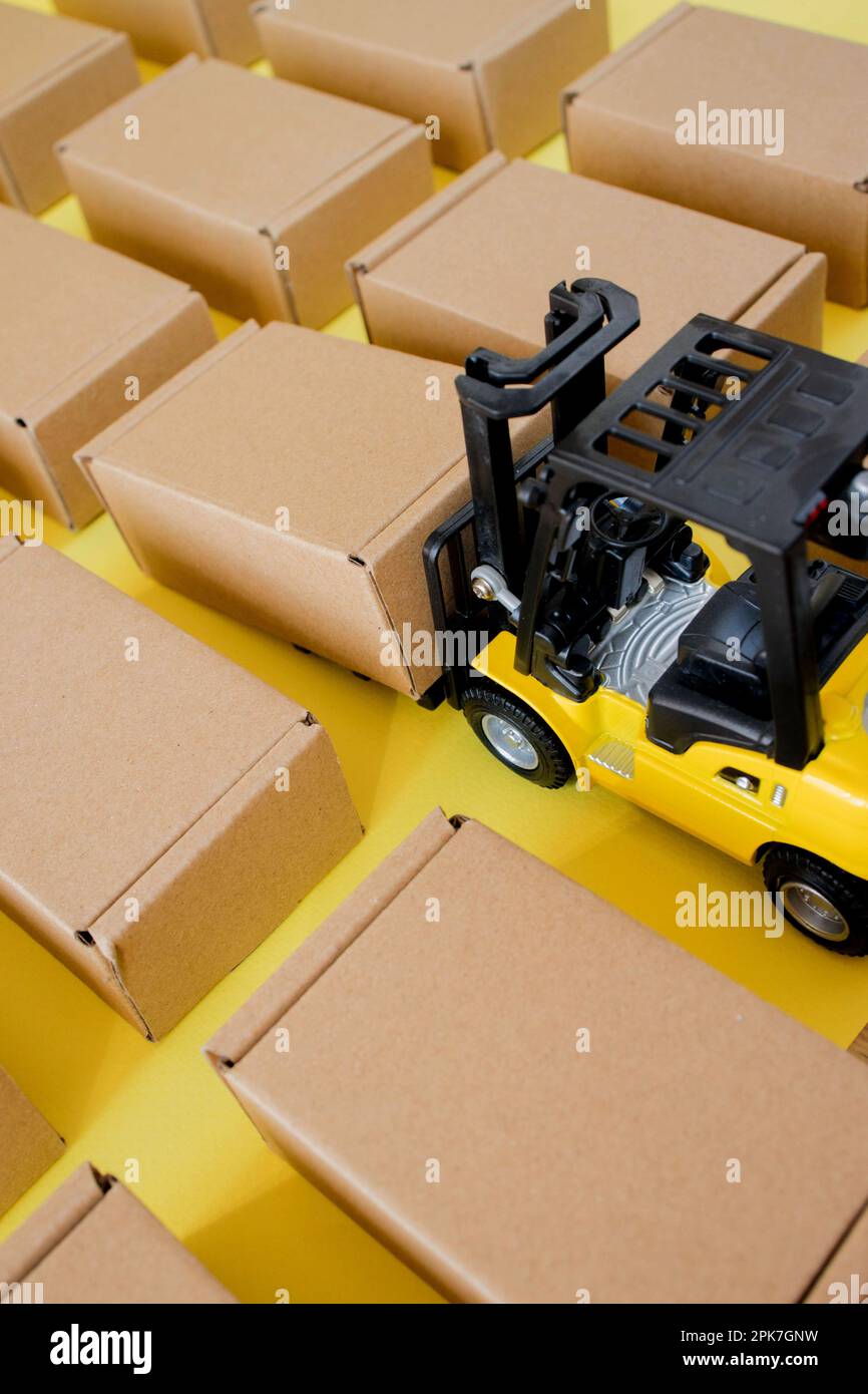 Forklift truck raises cardboard boxes on a yellow background. Cargo ...
