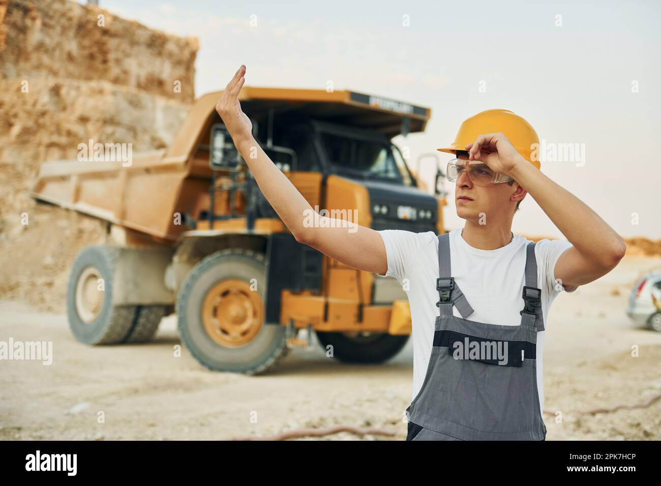 Professional loading vehicle. Worker in uniform is on the borrow pit at daytime Stock Photo - Alamy