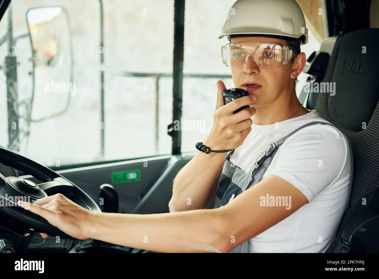 Driving transport. Worker in professional uniform is on the borrow pit at daytime Stock Photo ...