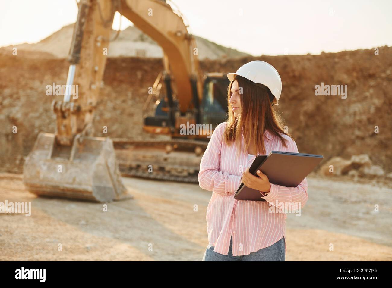 Young woman with documents in hard hat is standing on the borrow pit Stock Photo - Alamy