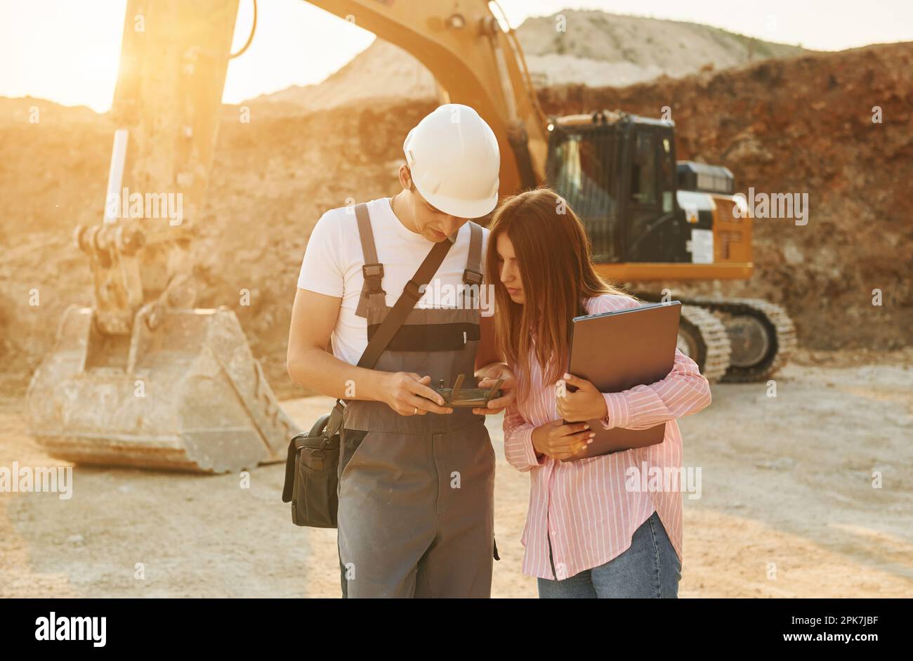 Successful teamwork. Two people is on the borrow pit at daytime ...
