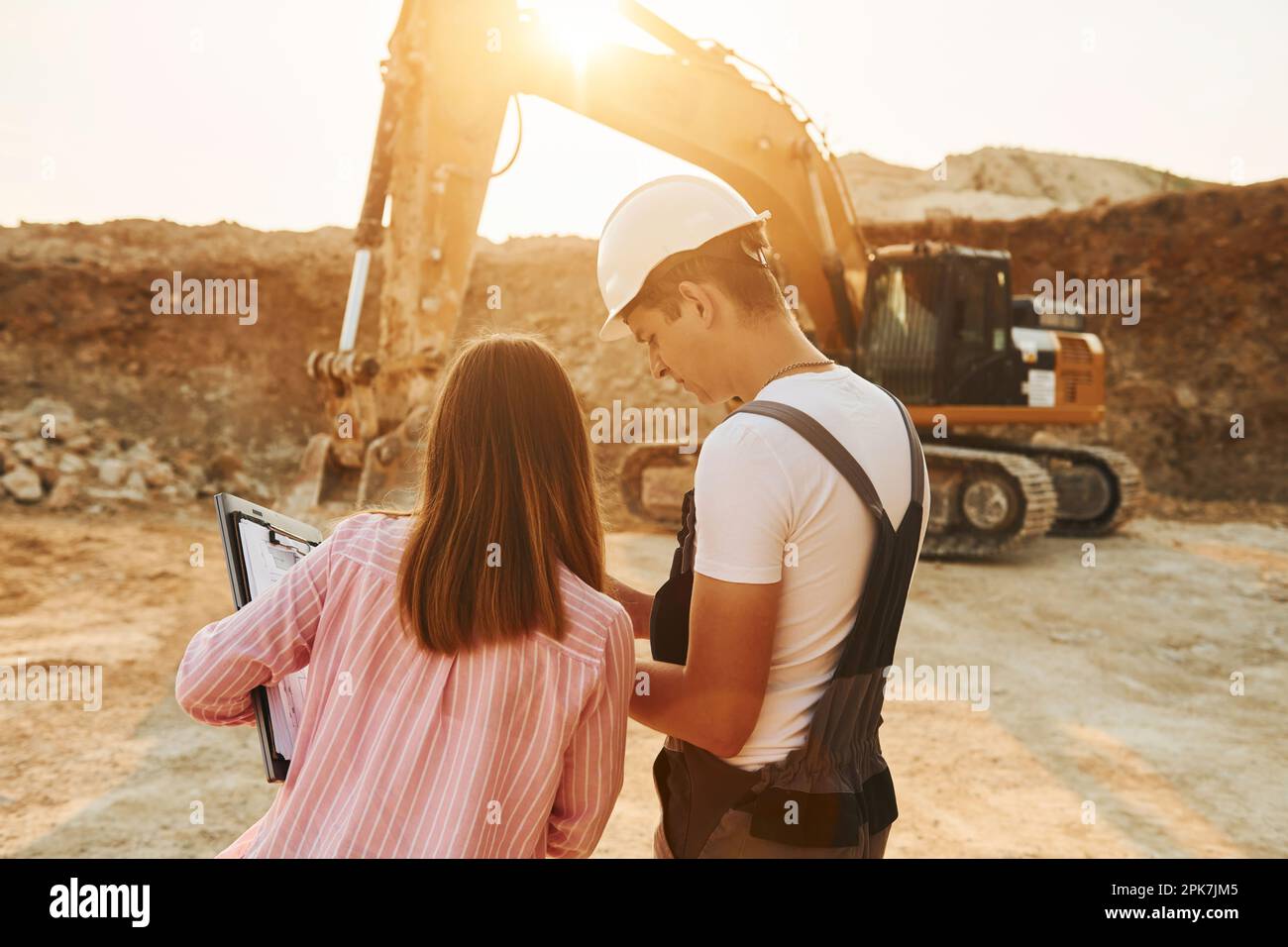 Talking about plan. Two workers is on the borrow pit at daytime together Stock Photo - Alamy