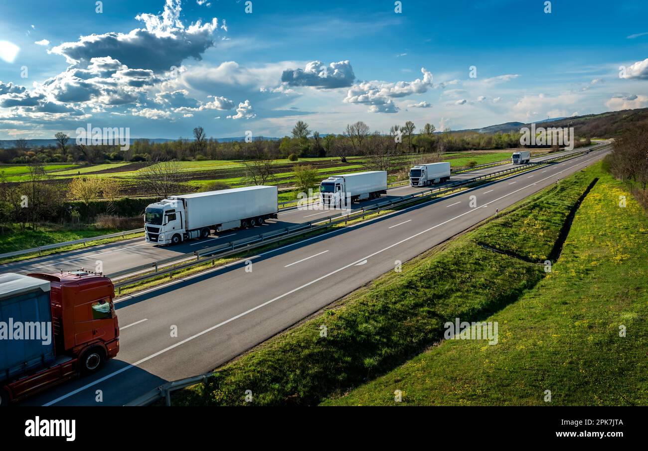 Highway transportation scene with Convoy of white transportation trucks ...