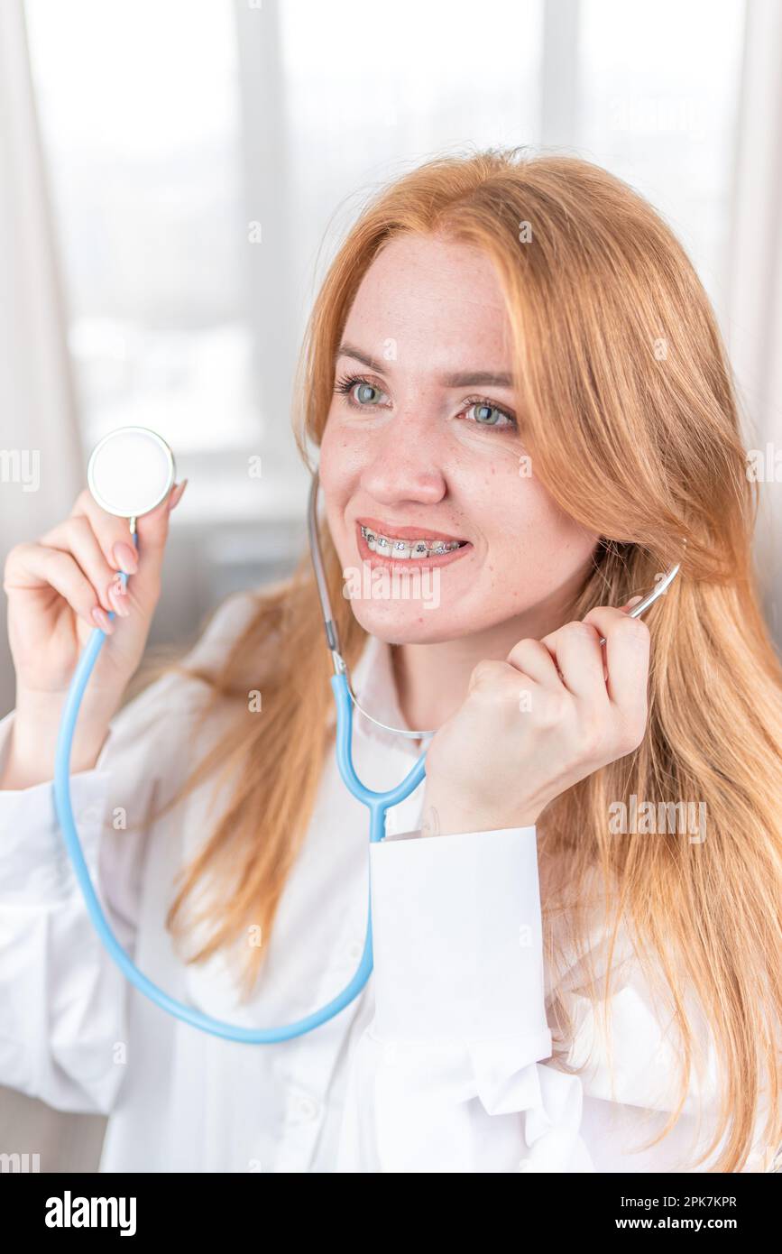 Medical concept. Smiling nurse girl with braces and a stethoscope in ...