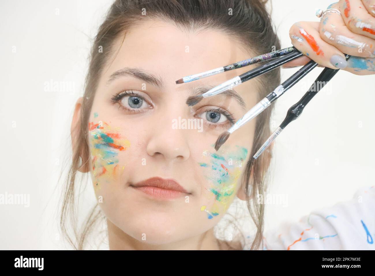 Girl with blue eyes painting with colored paints and pencils. Portrait ...