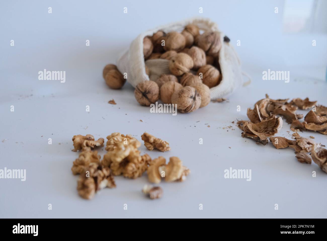 Walnut kernels, walnut shells and a white cloth bag full of whole ...