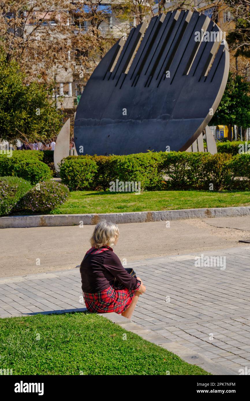Woman sits in front of the Promahones sculpture in the gardens of the ...