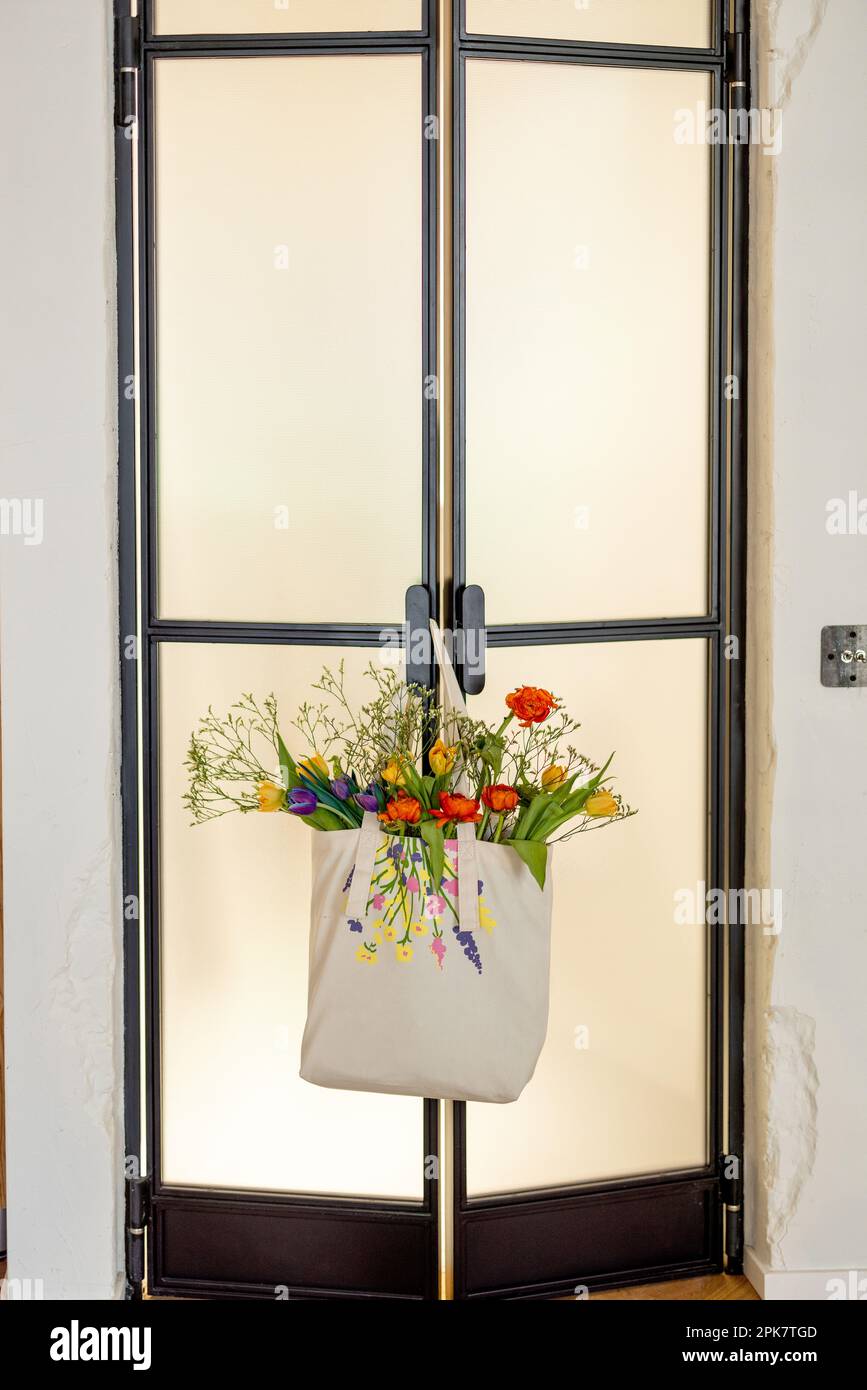 Bag with fresh flowers hanging on glass door Stock Photo - Alamy