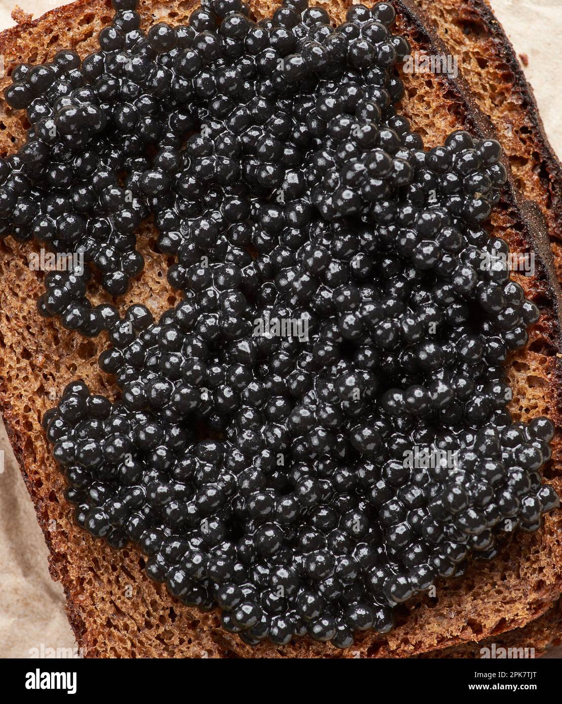 Black caviar spread on a piece of rye bread, top view Stock Photo - Alamy