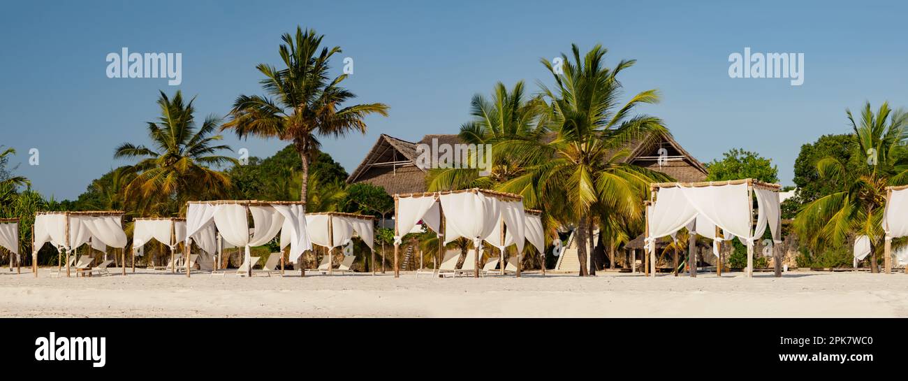 Sun loungers covered with white, airy curtains in a luxurious resort by ...