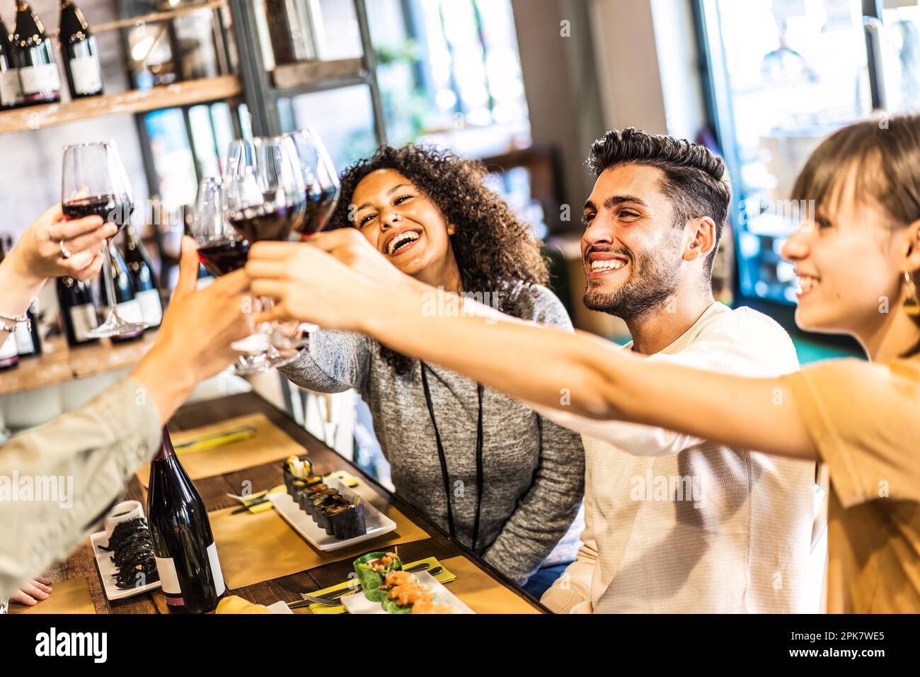 Multiethnic friends toasting red wine at sushi restaurant - Food and ...