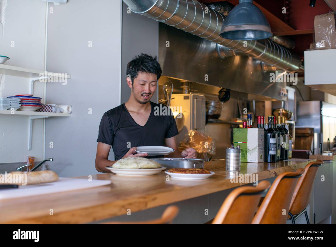 A chef working in a restaurant, at the pass preparing plates of food ...