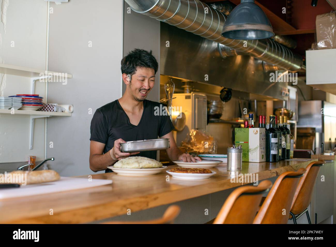 A chef working in a restaurant, at the pass preparing plates of food ...