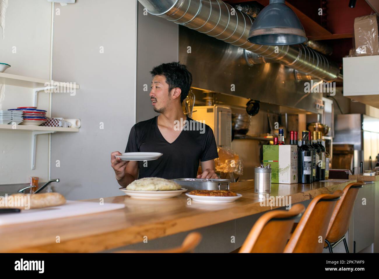 A chef working in a restaurant, at the pass preparing plates of food ...
