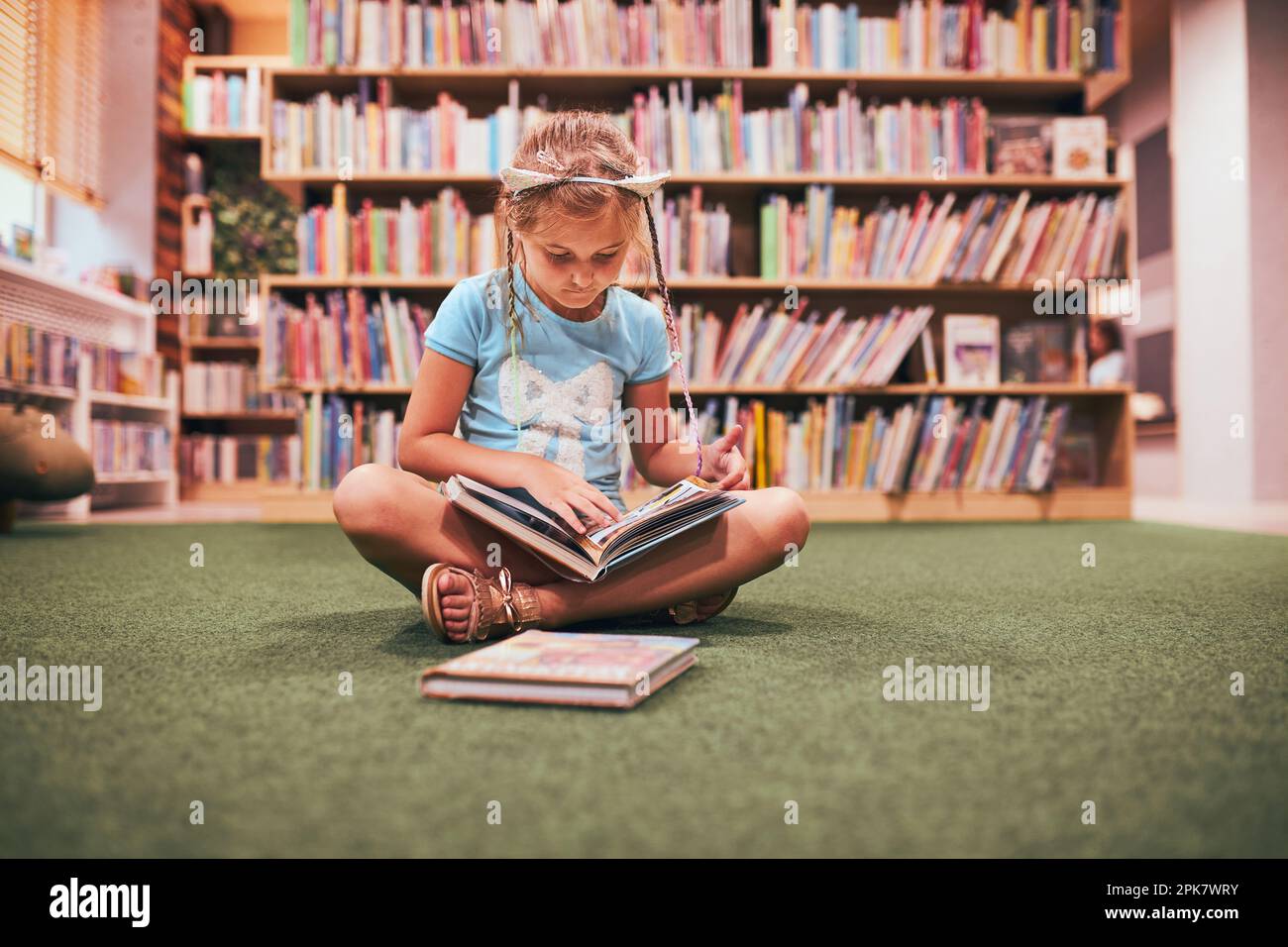 Primary schoolgirl doing homework in school library. Student learning ...