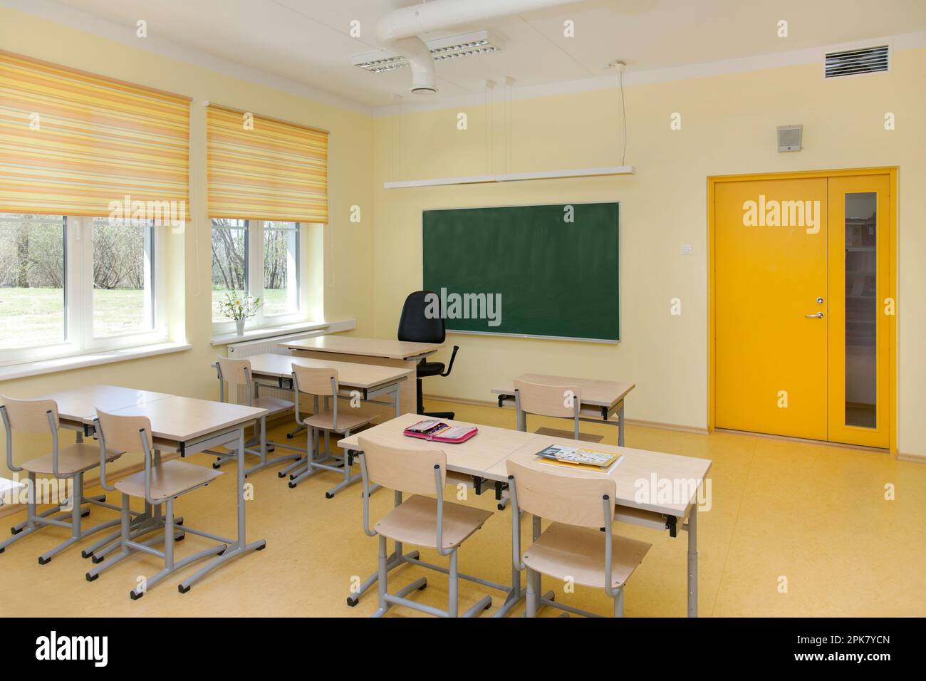 A newly built school classroom with desk and chairs. Windows with ...