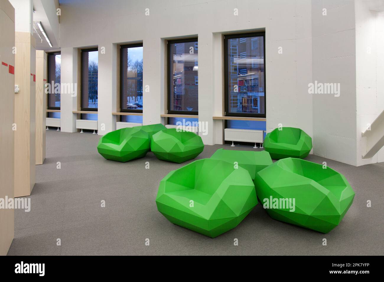 A healthcare college library with open spaces, green chairs and book ...