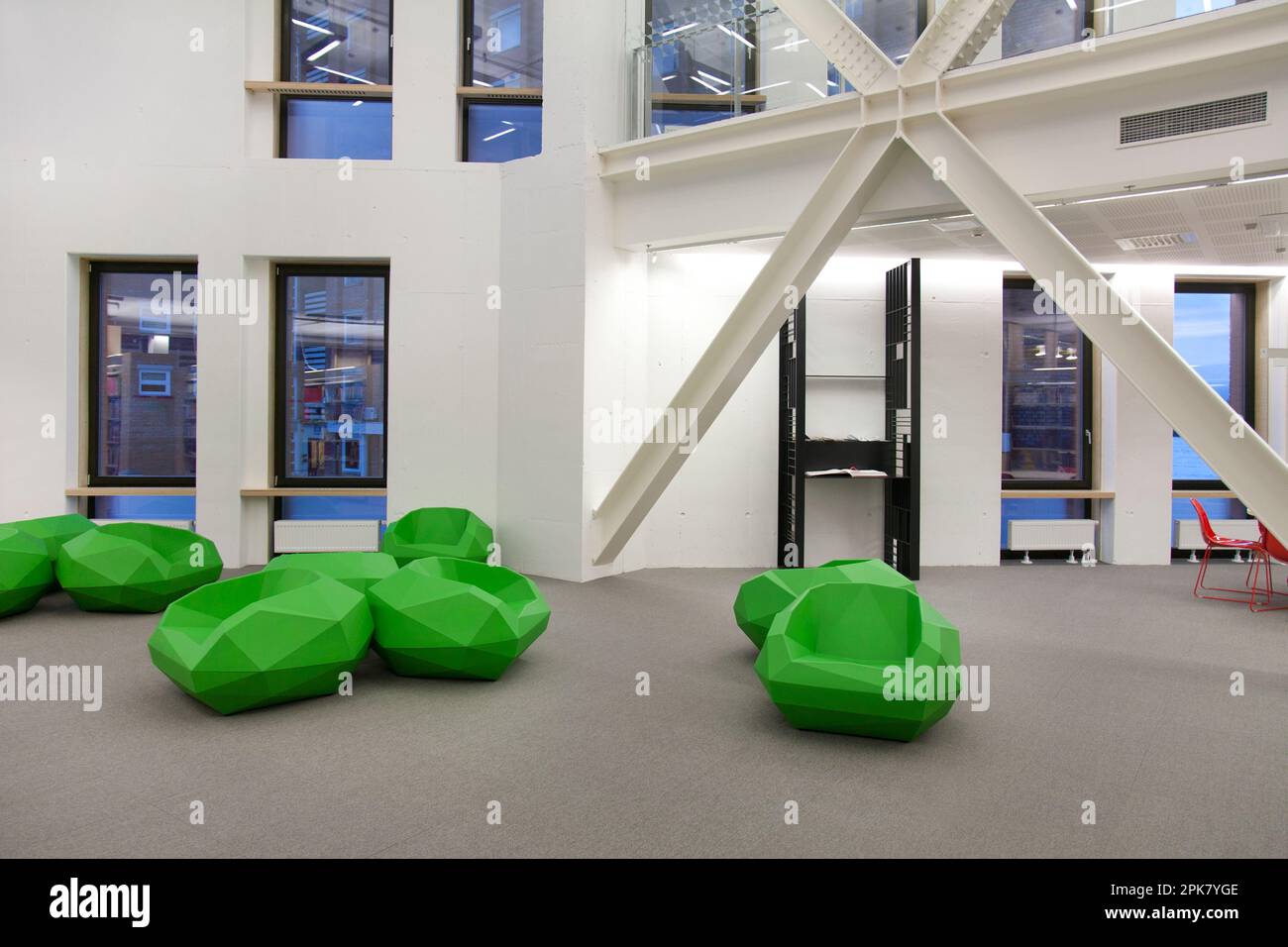 A healthcare college library with open spaces, green chairs and book ...