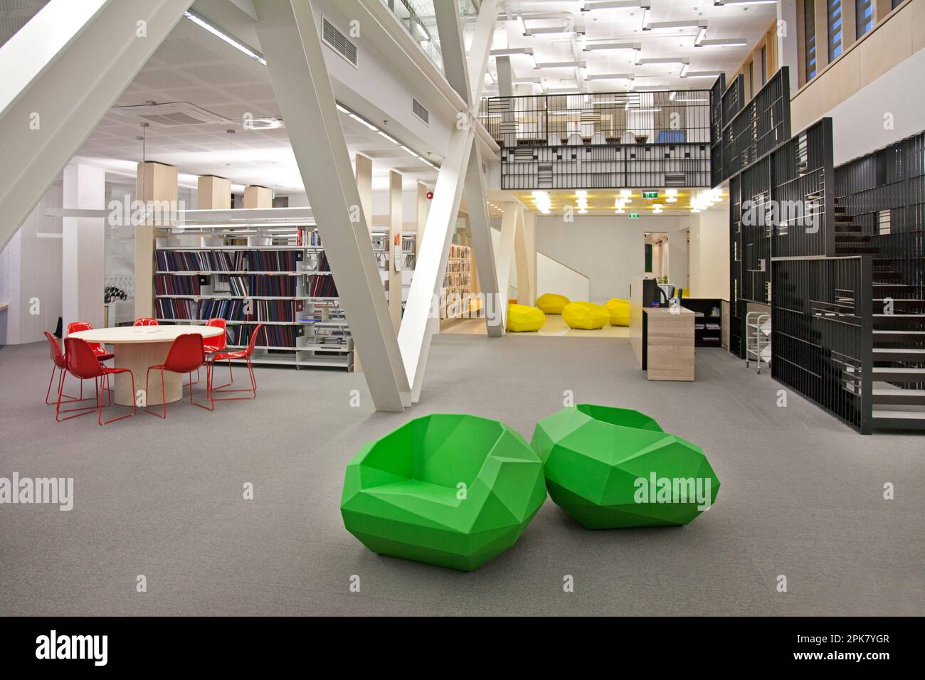 A healthcare college library with open spaces, green chairs and book ...