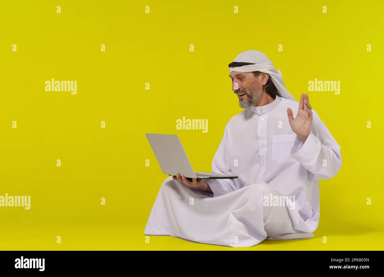 Concept online communication. Muslim person sitting on floor greets ...