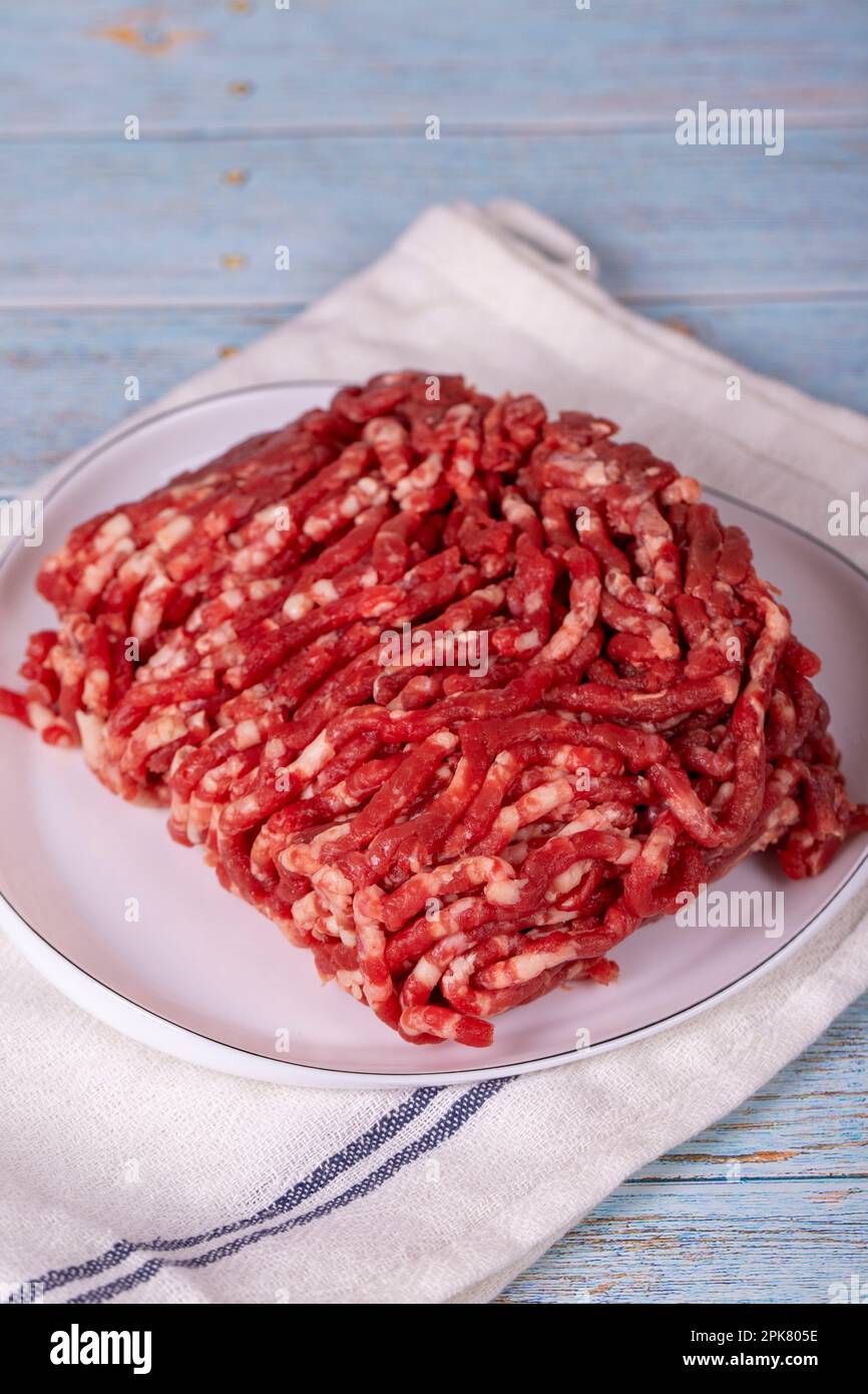 Beef minced on the plate. Fresh ground beef on wood background. Close ...