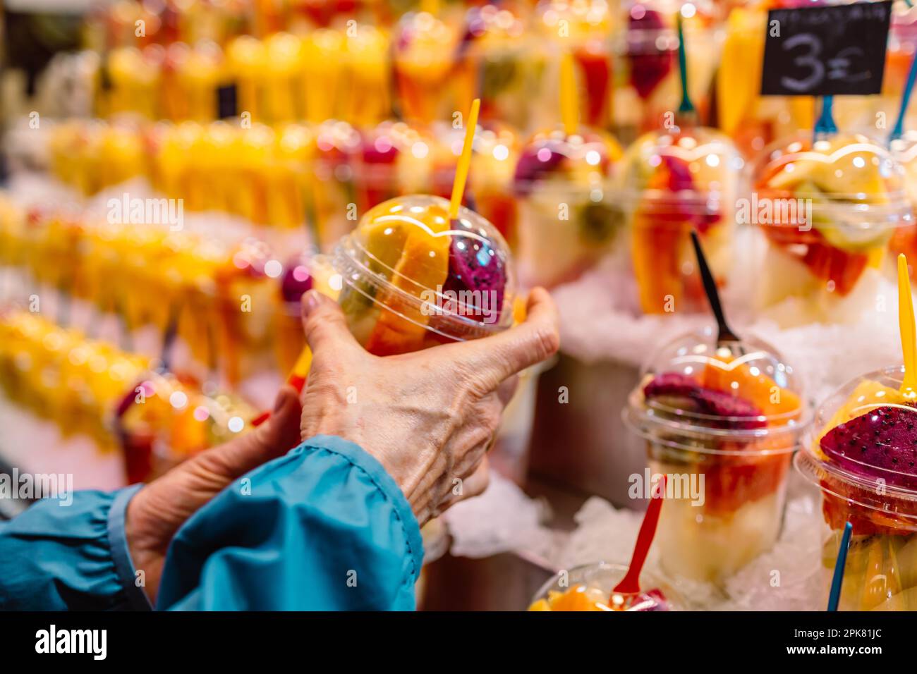 Woman choosing and takes a prepared fruit salad pots to take away in ...