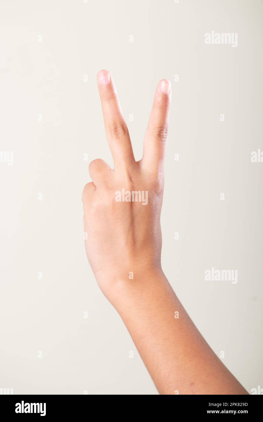 Female hand victory sign gesture on grey background Stock Photo - Alamy