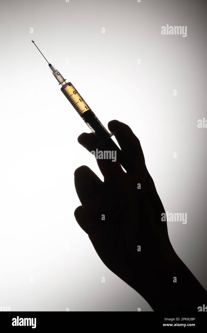 Shadow of injection in hand, drug dose Stock Photo - Alamy