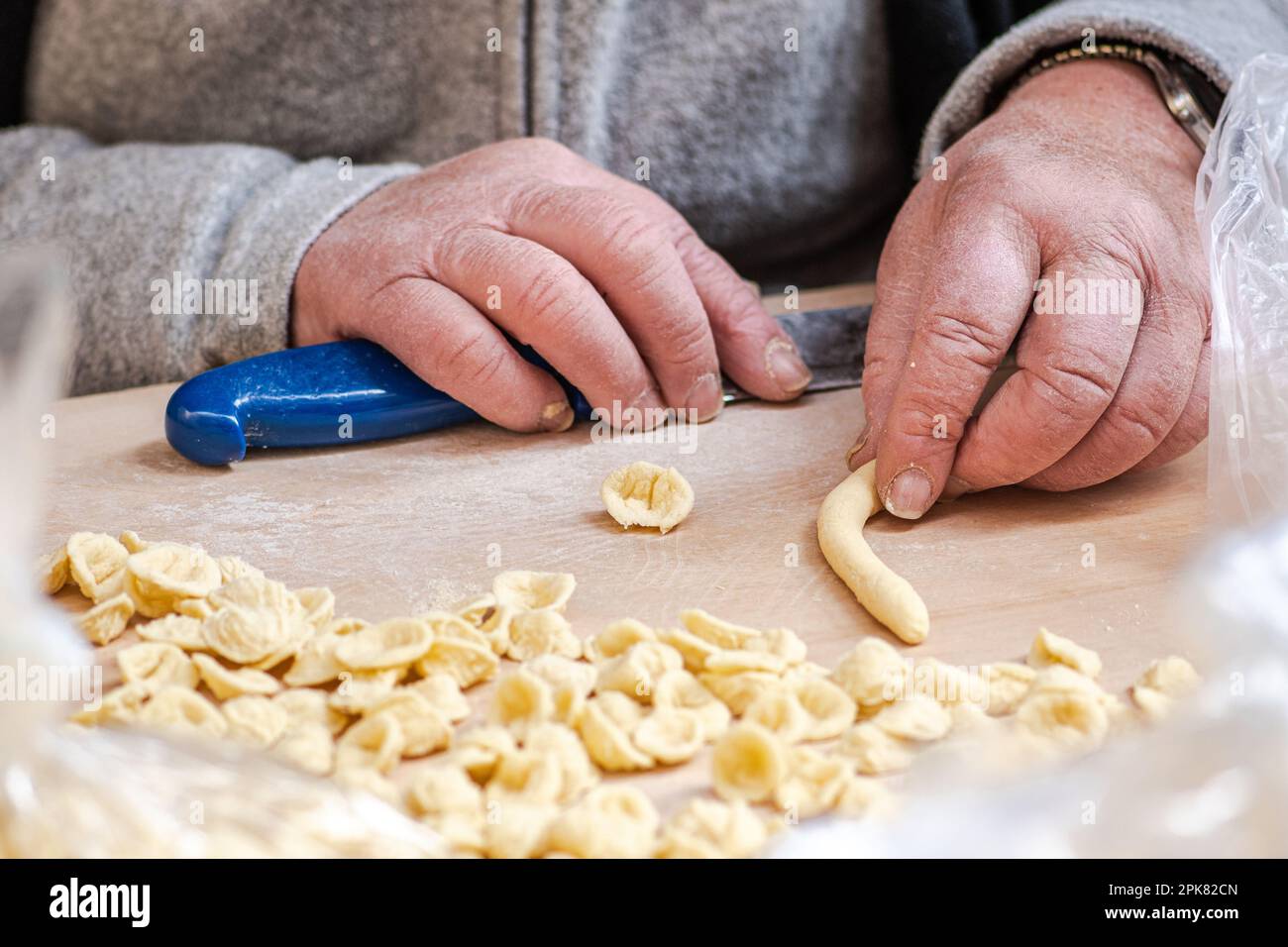 Wrinkled hands of an elderly woman preparing fresh orecchiette or ...
