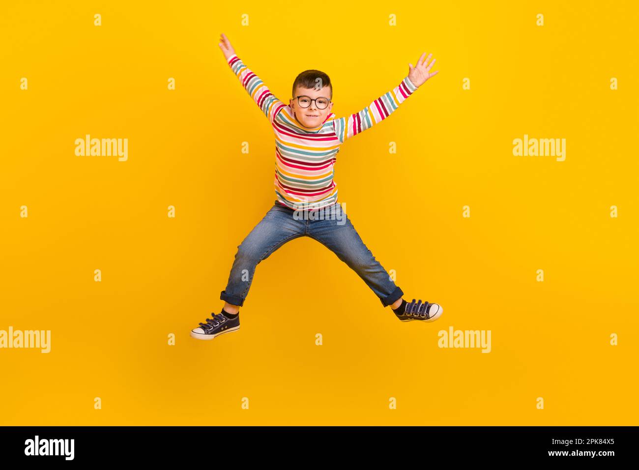 Full length photo of active kid boy jumping up raising hands isolated ...