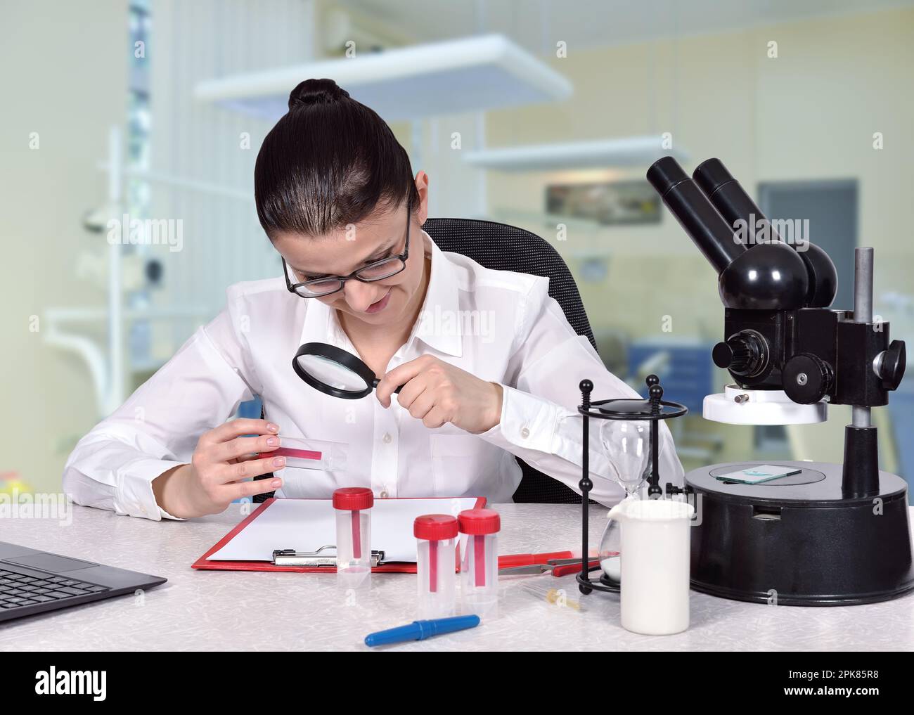 female scientist examines a sample through a magnifying glass Stock ...