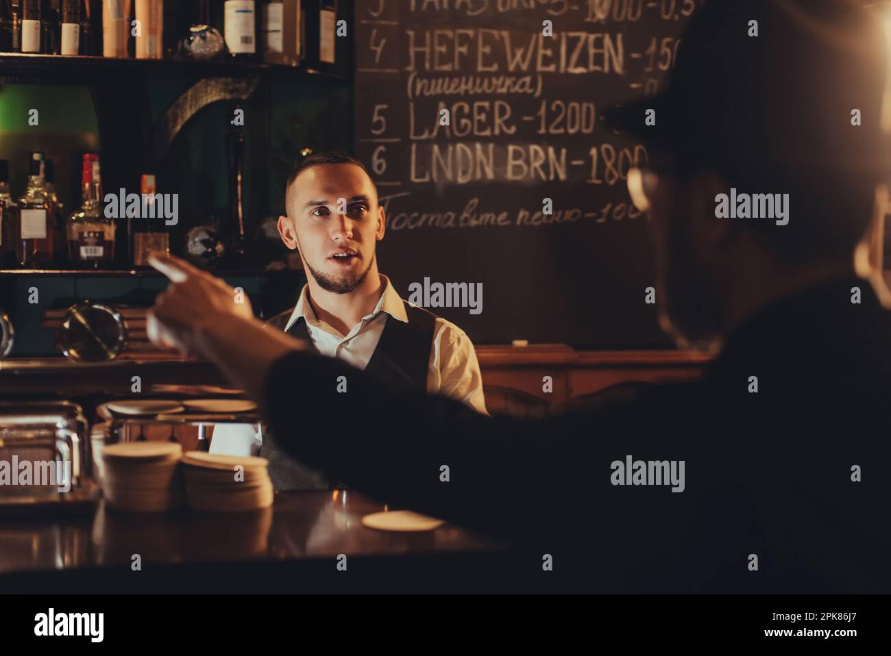 man orders an alcoholic drink from a bartender in a bar Stock Photo - Alamy