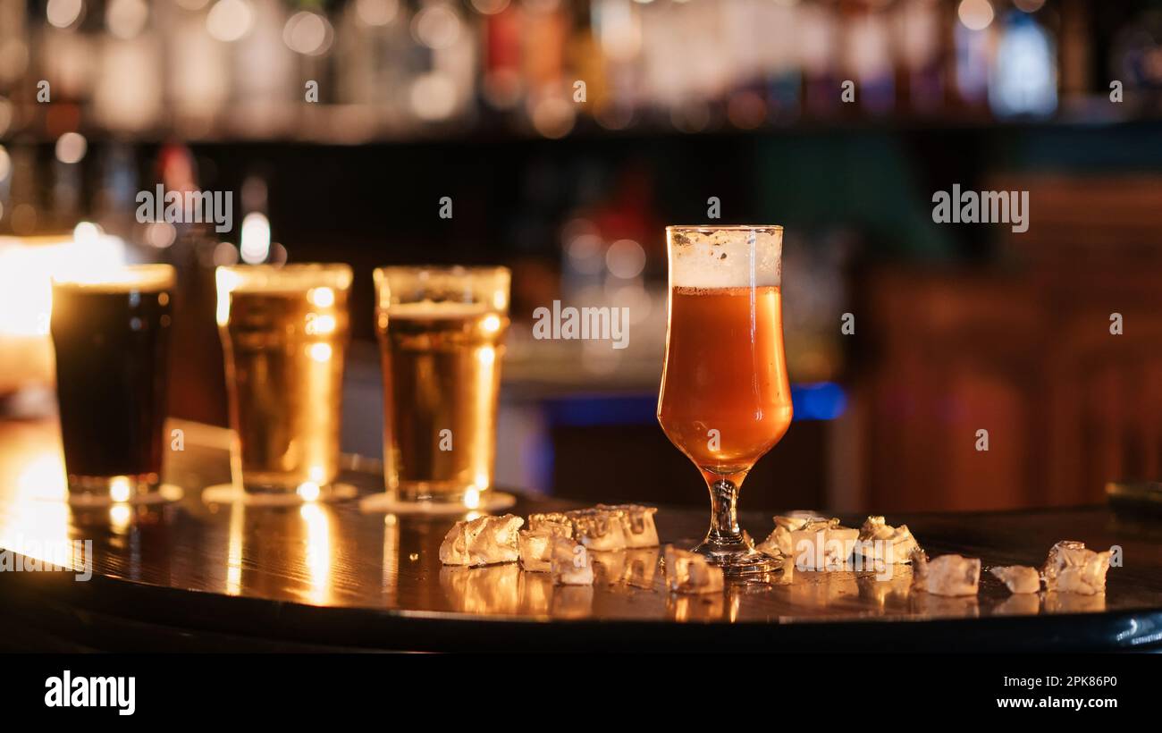glass of unfiltered draft golden beer on bar counter with ice in ...