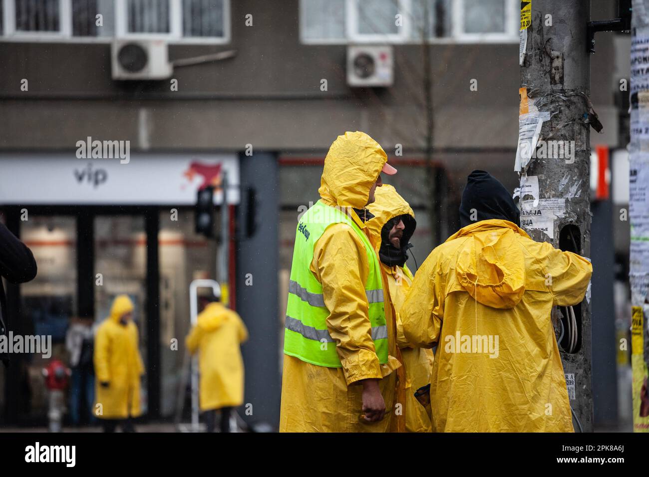 Picture of men wearing a yellow rain coat working outdoors fixing ...