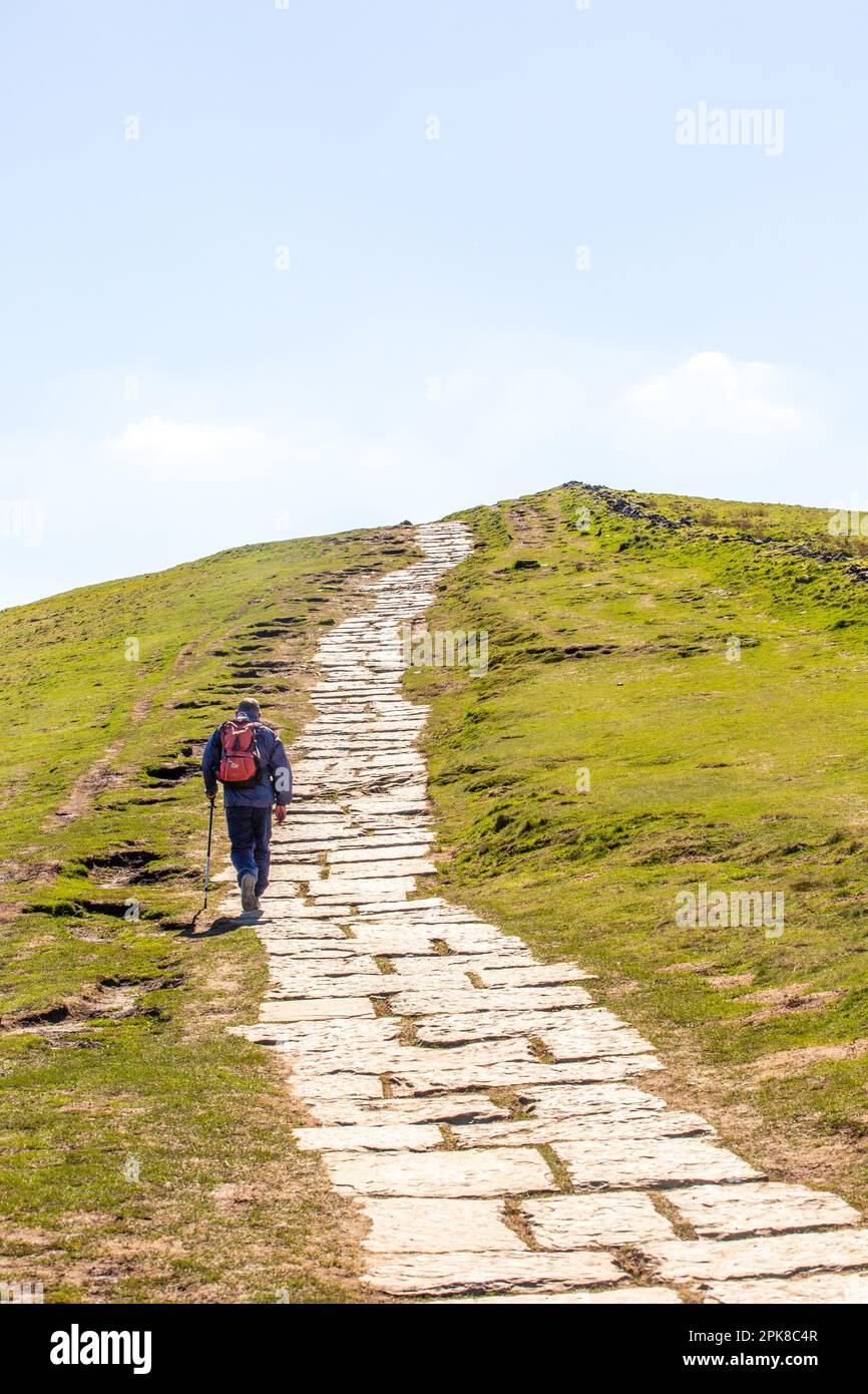 Man climbing the flagstones up to the summit of Mam Tor the highest ...