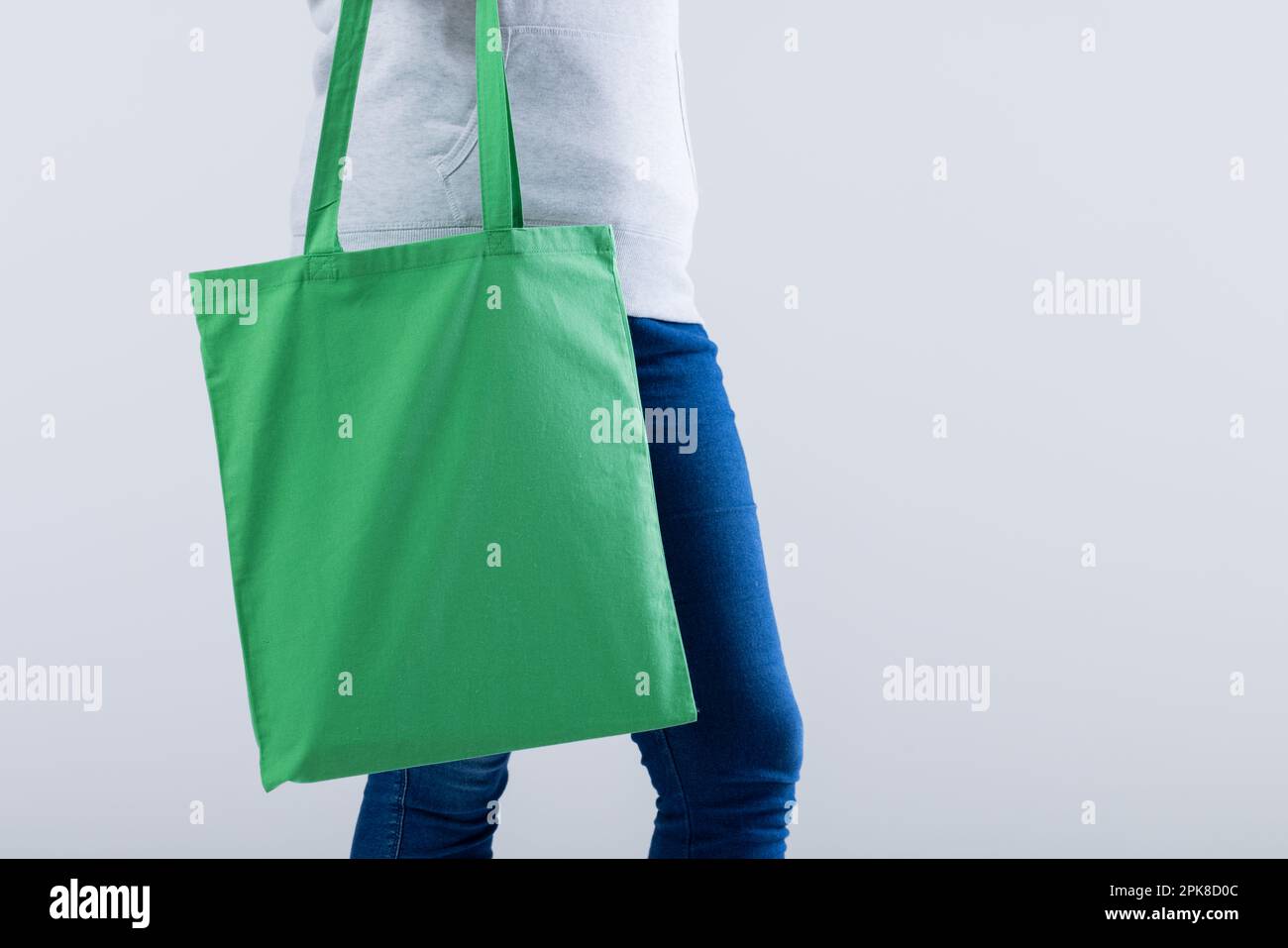 Caucasian woman holding green canvas bag with copy space on grey ...