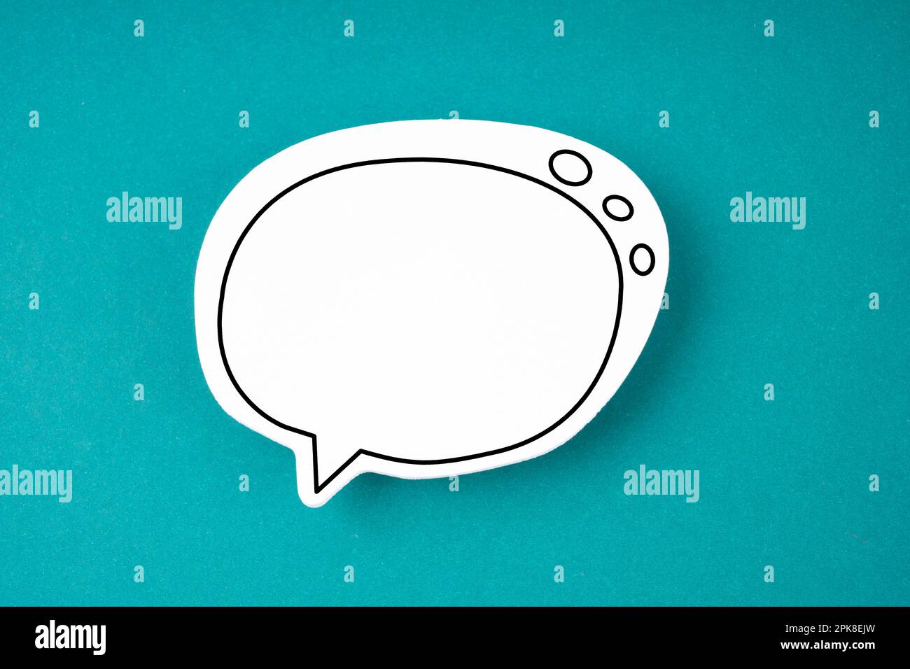 White speech bubble shaped post it note on green background with copy ...