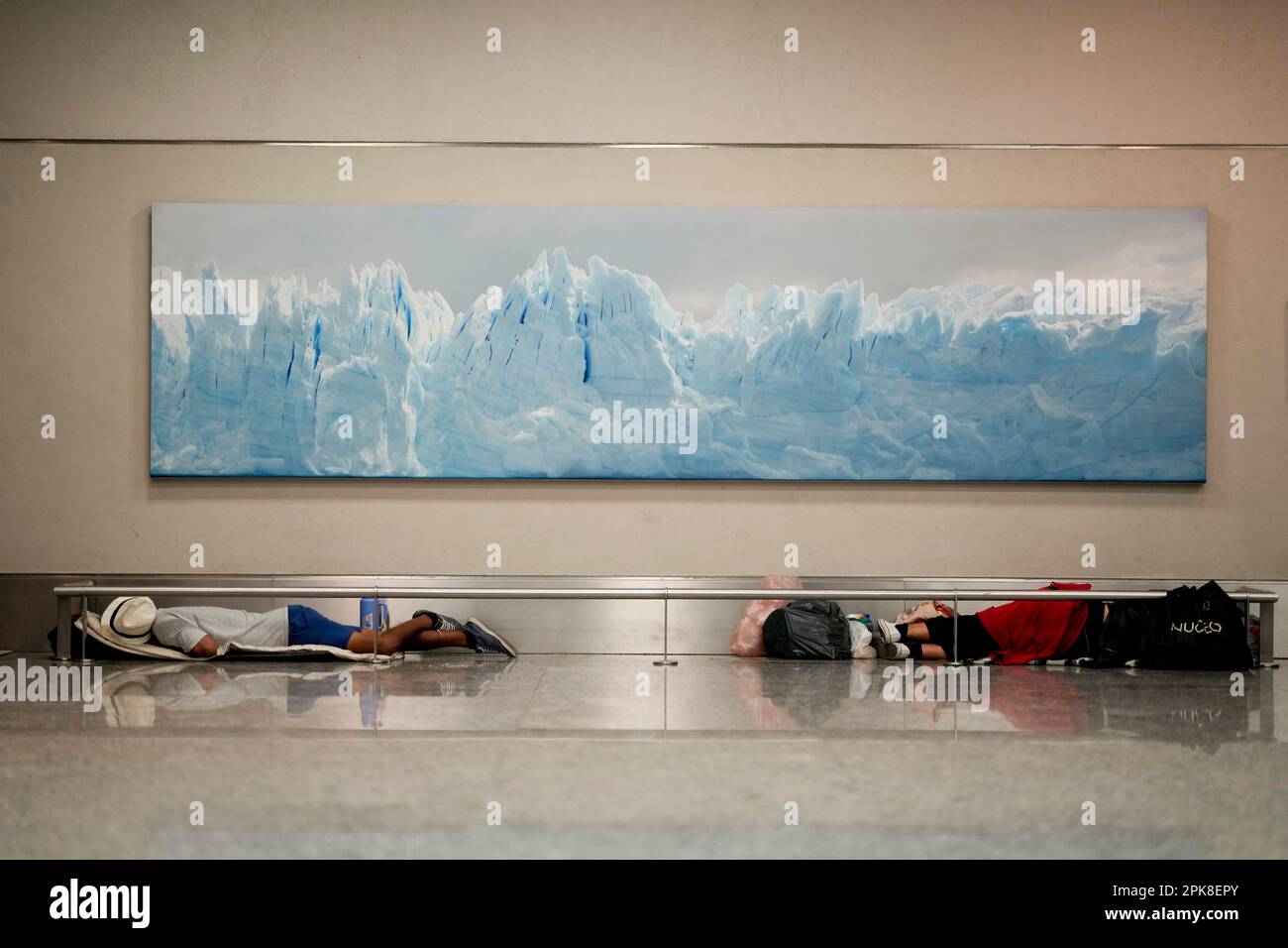 Homeless men sleep below a photo of the Perito Moreno Glacier at the ...