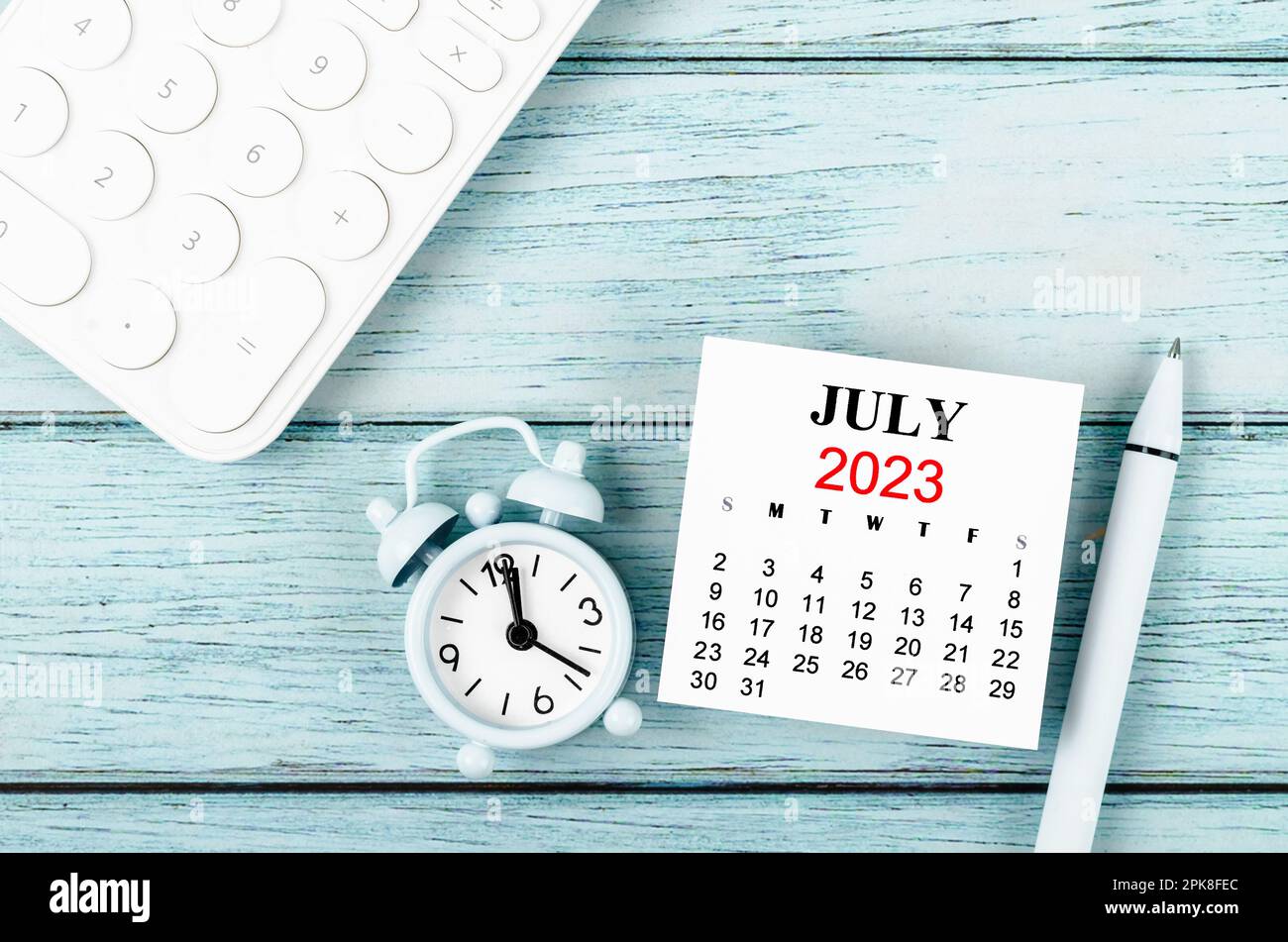 July 2023 Monthly calendar year and alarm clock with calculator on blue ...