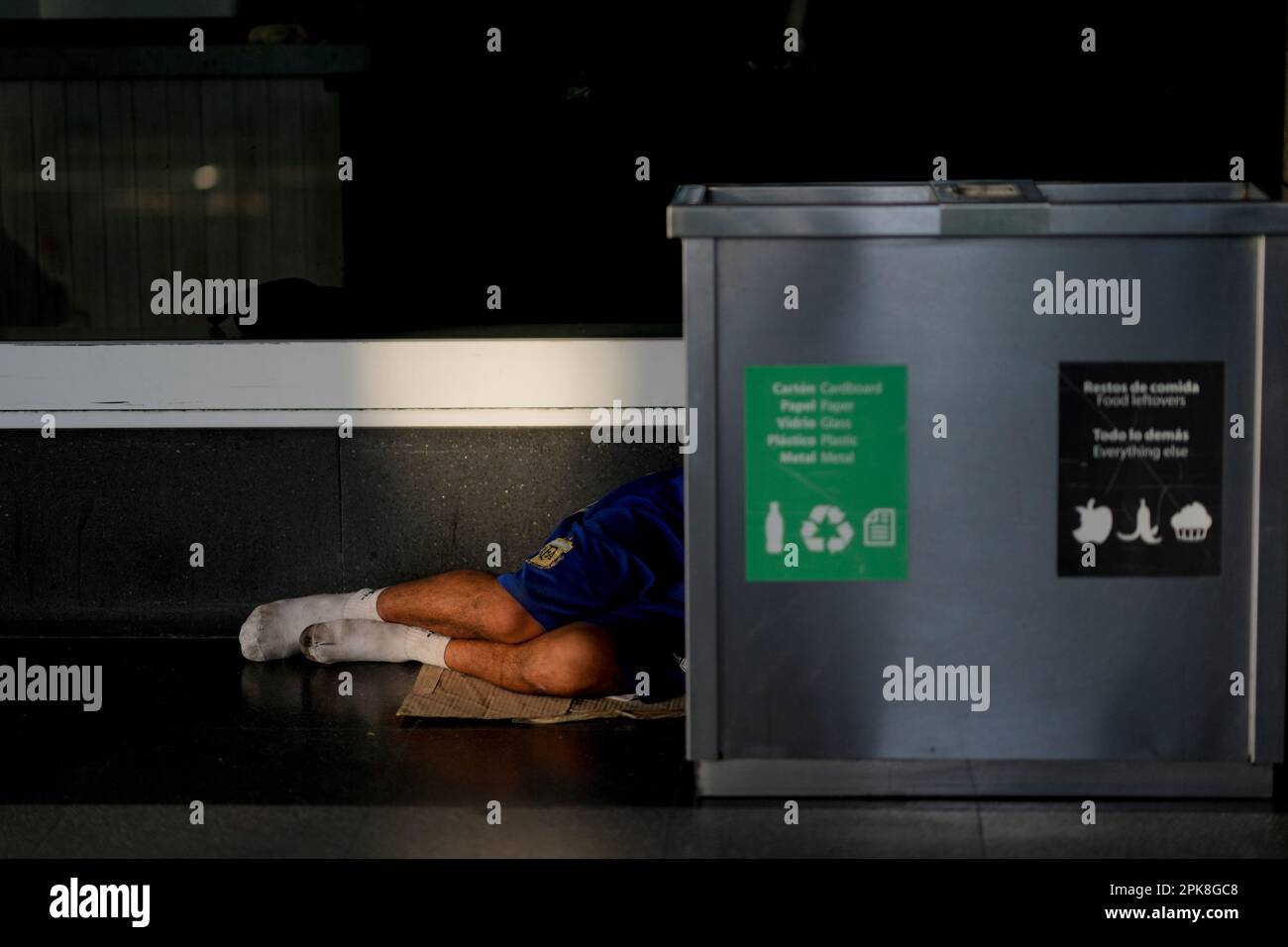 A homeless man sleeps behind a bin at the Jorge Newbery international ...