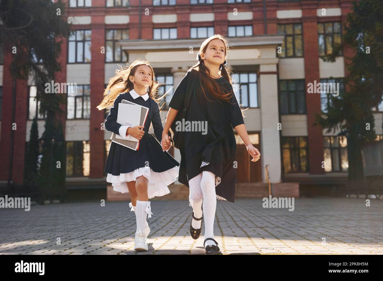 Two schoolgirls is running outside together near school building Stock ...
