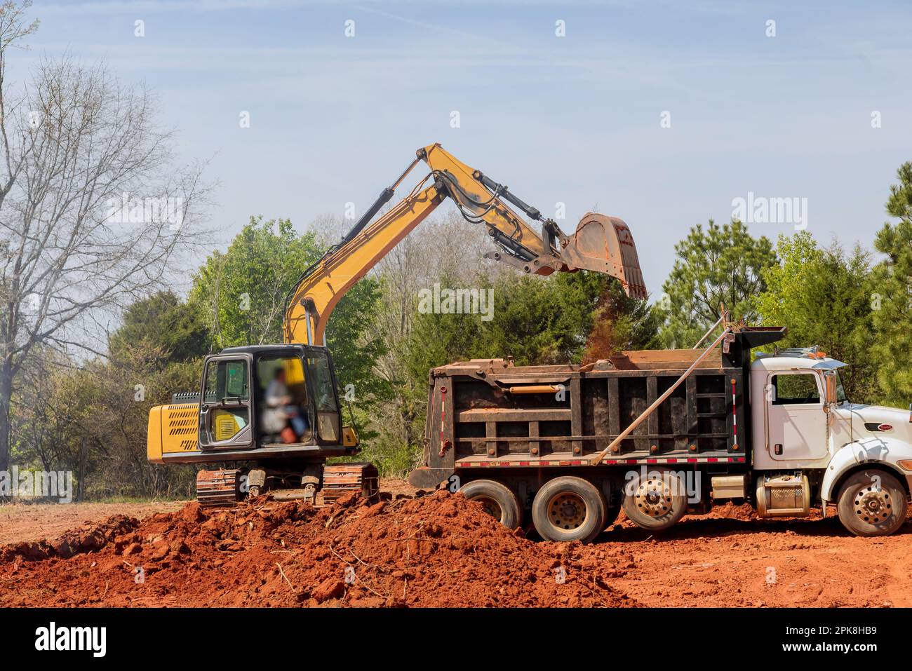 Dump truck is loading earth into an excavator on construction site Stock Photo - Alamy