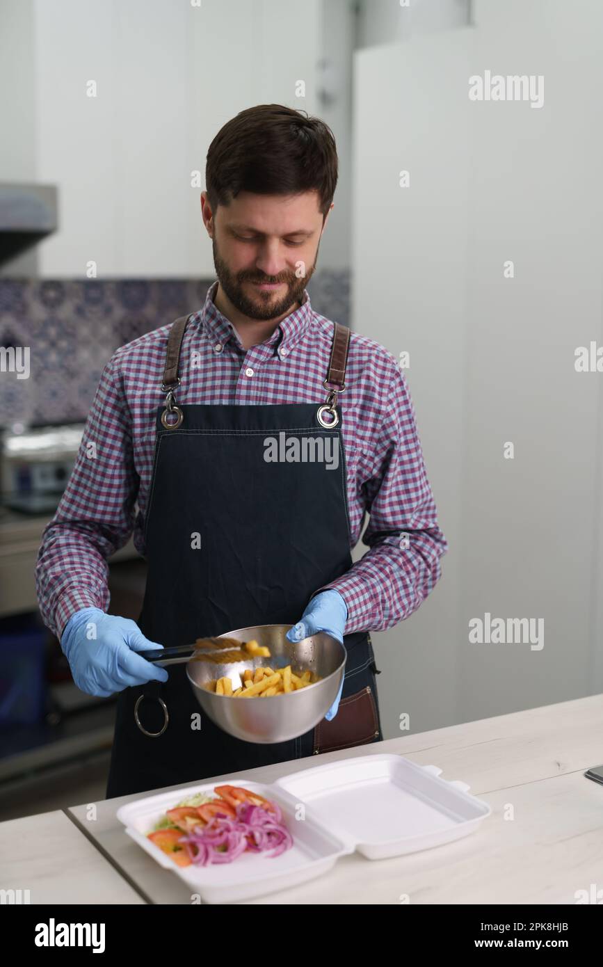 Cheerful white man preparing traditional Greek fast food in a ...