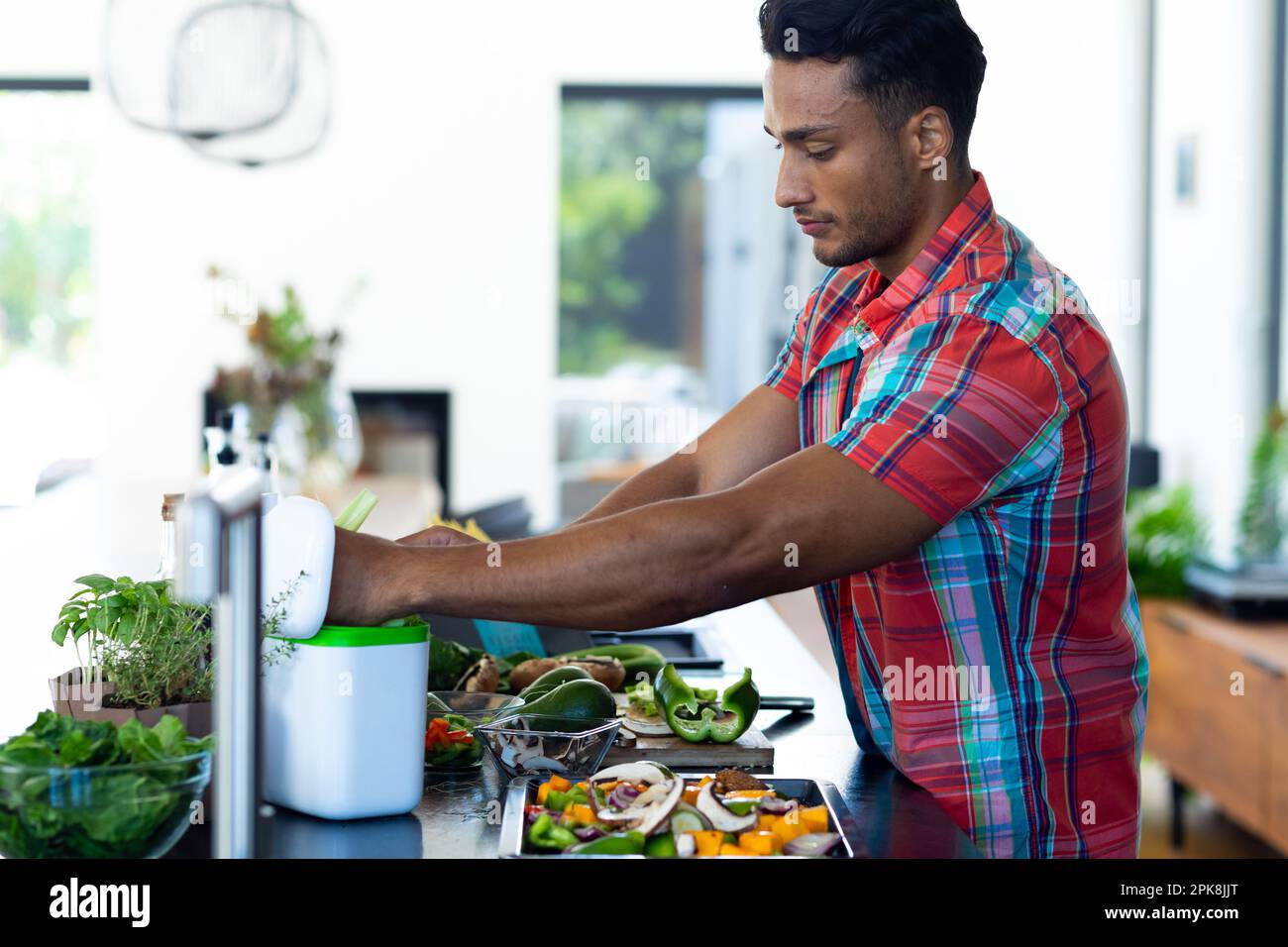 Happy biracial man preparing dinner, chopping vegetables and composting ...