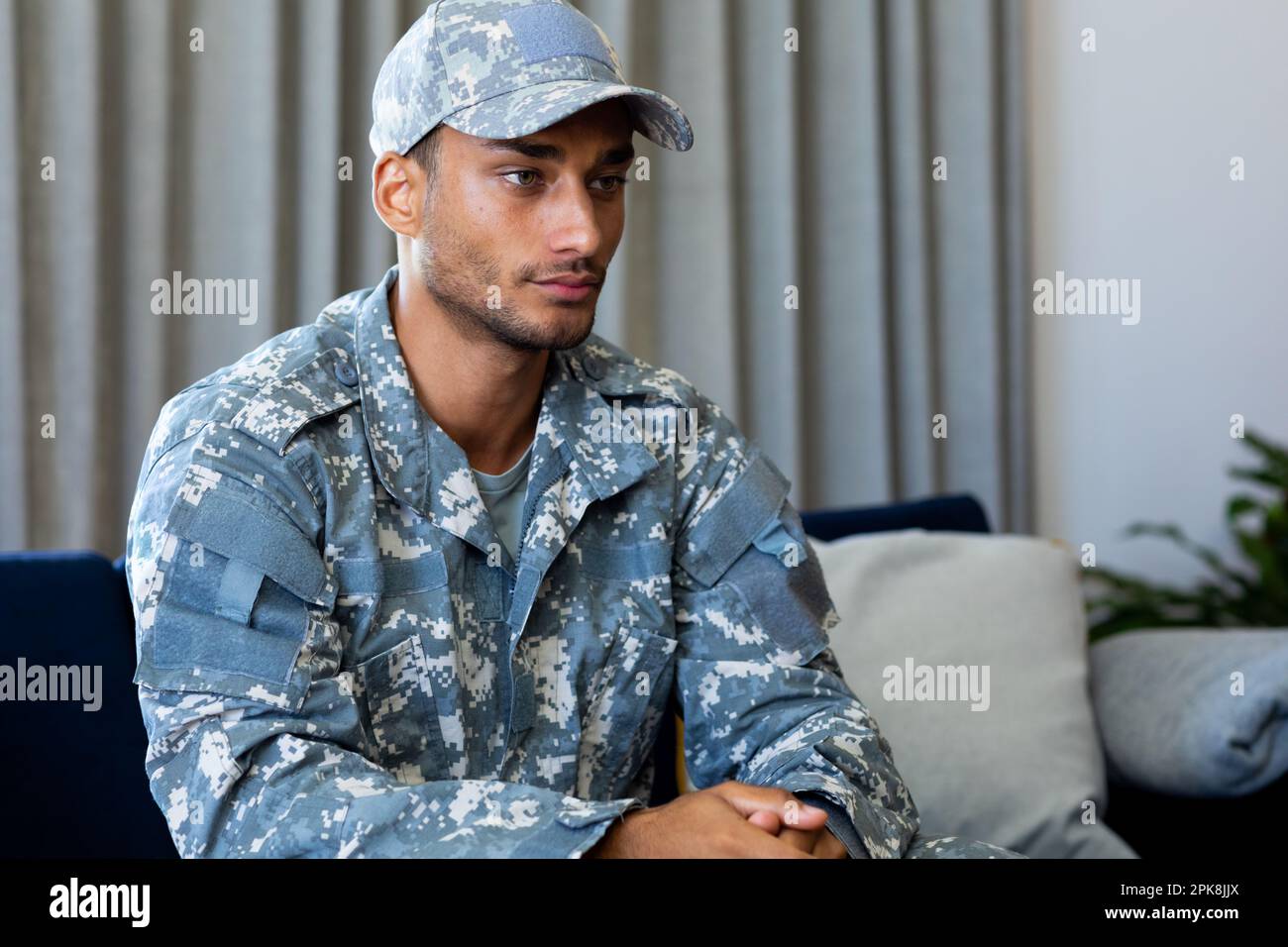 Thoughtful biracial male soldier wearing military uniform and cap ...