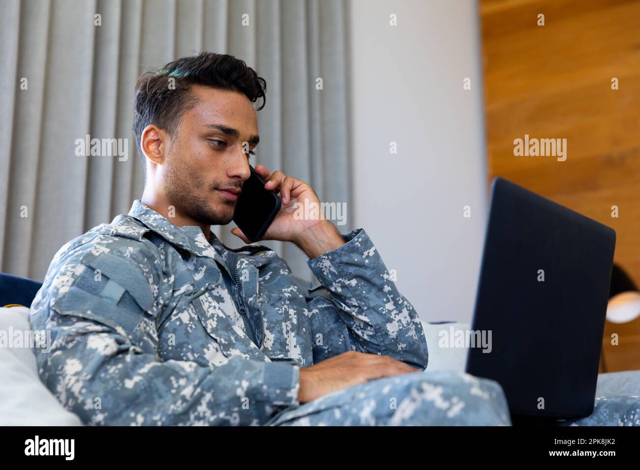 Biracial male soldier wearing uniform using laptop and talking on ...