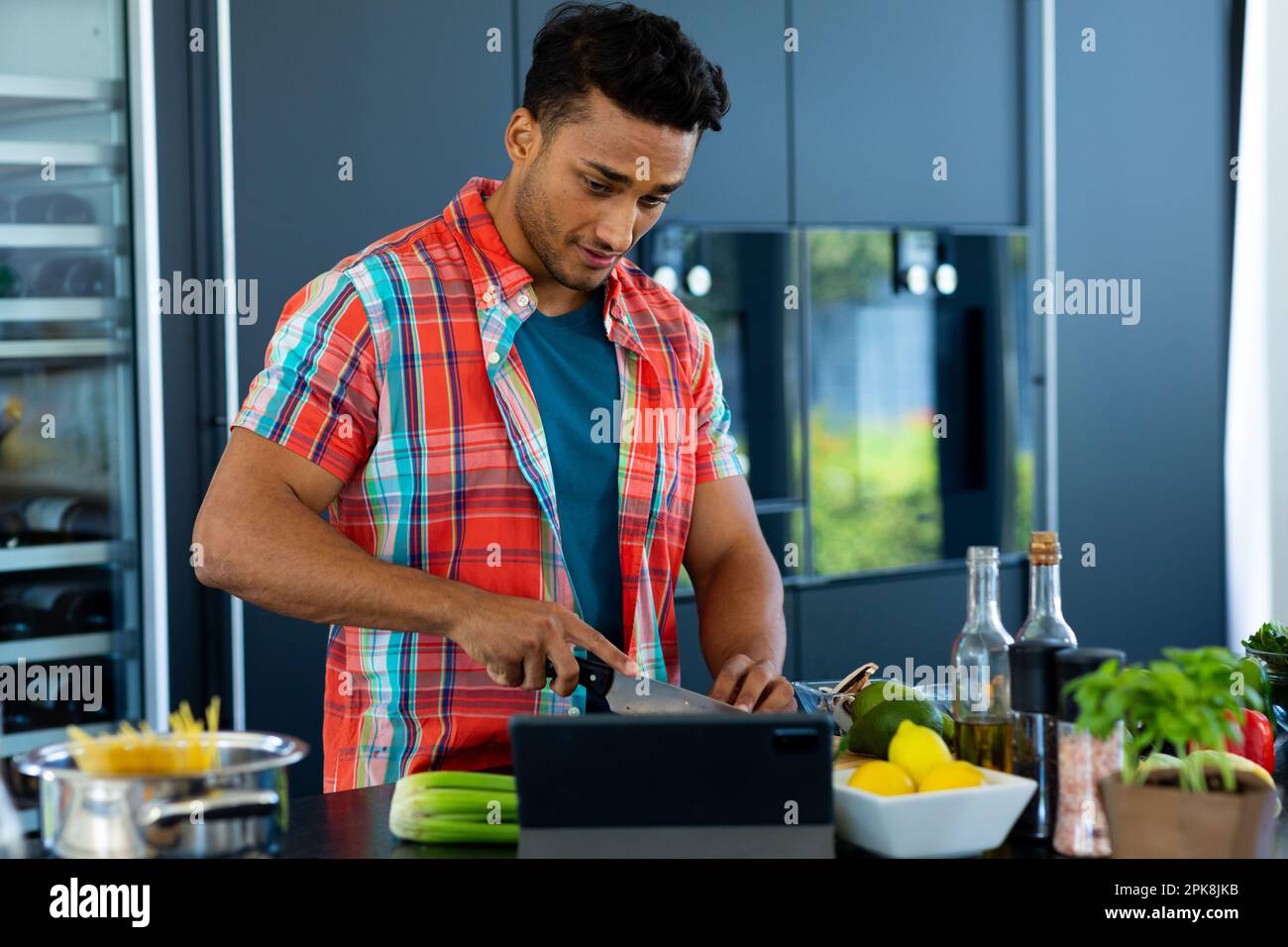 Happy biracial man preparing dinner, chopping vegetables in kitchen ...